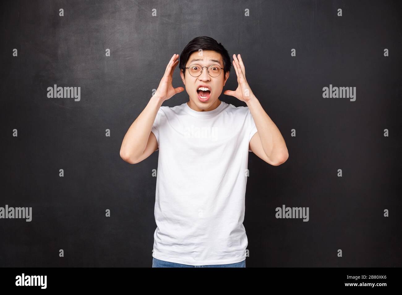 Alarmed and embarrassed young panicking asian guy, shaking hands near ...