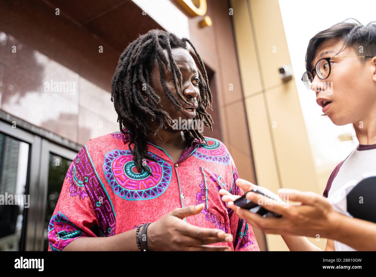 People of different ethnicities arguing in the street with a mobile ...