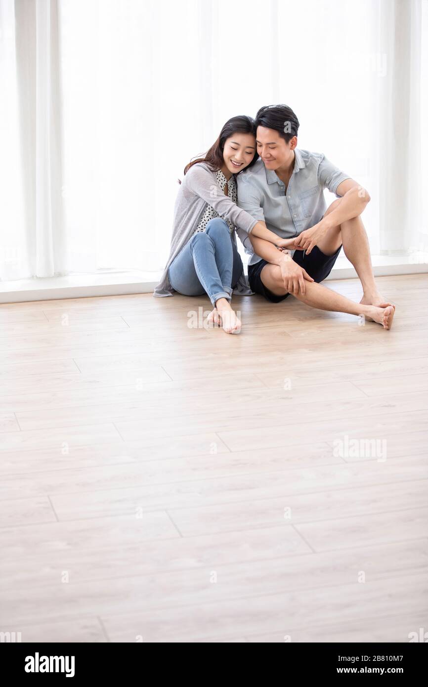 Happy young Chinese couple sitting on floor Stock Photo - Alamy