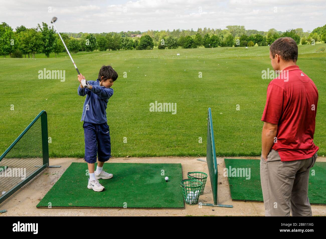 A young boy golfer demonstrating his teeing off skills under the ...