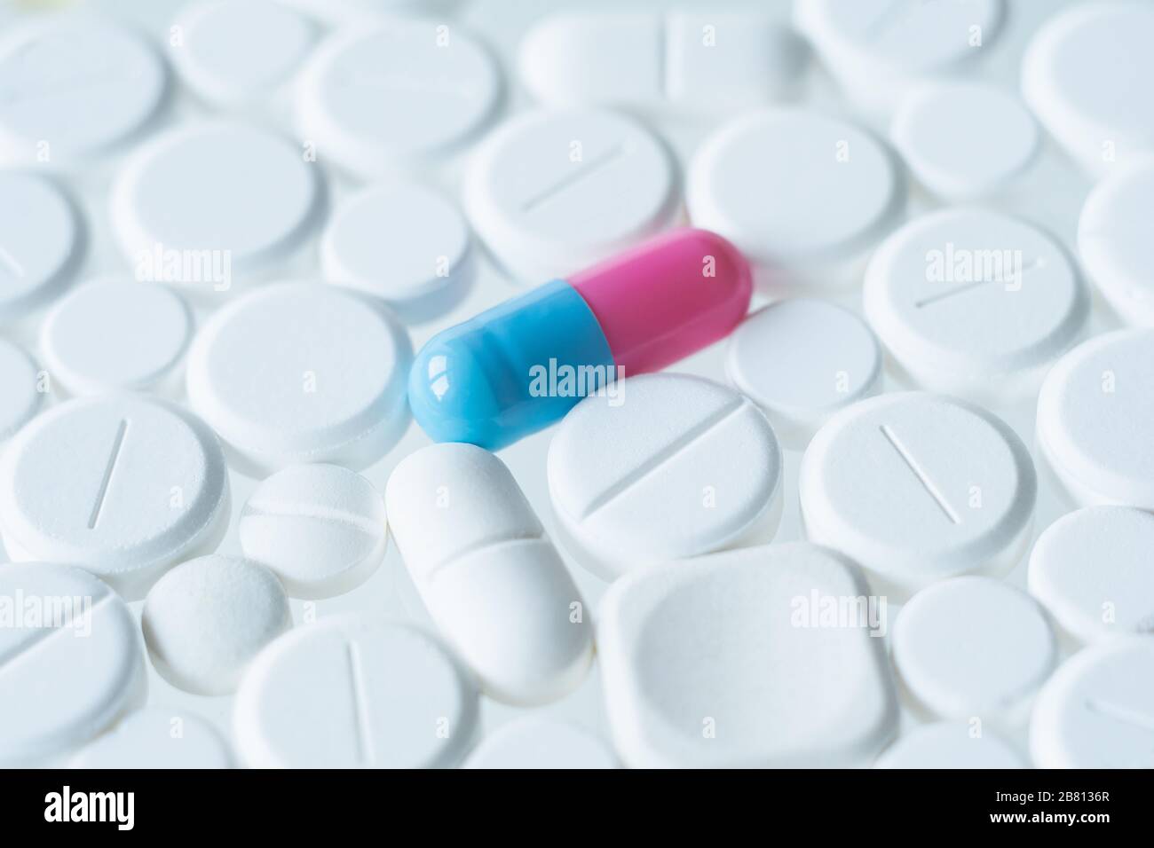 Red and blue pill lying among white drugs, conceptual image of unique ...