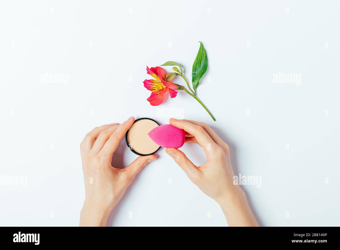 Makeup foundation and sponge blender in woman's hands next to a ...