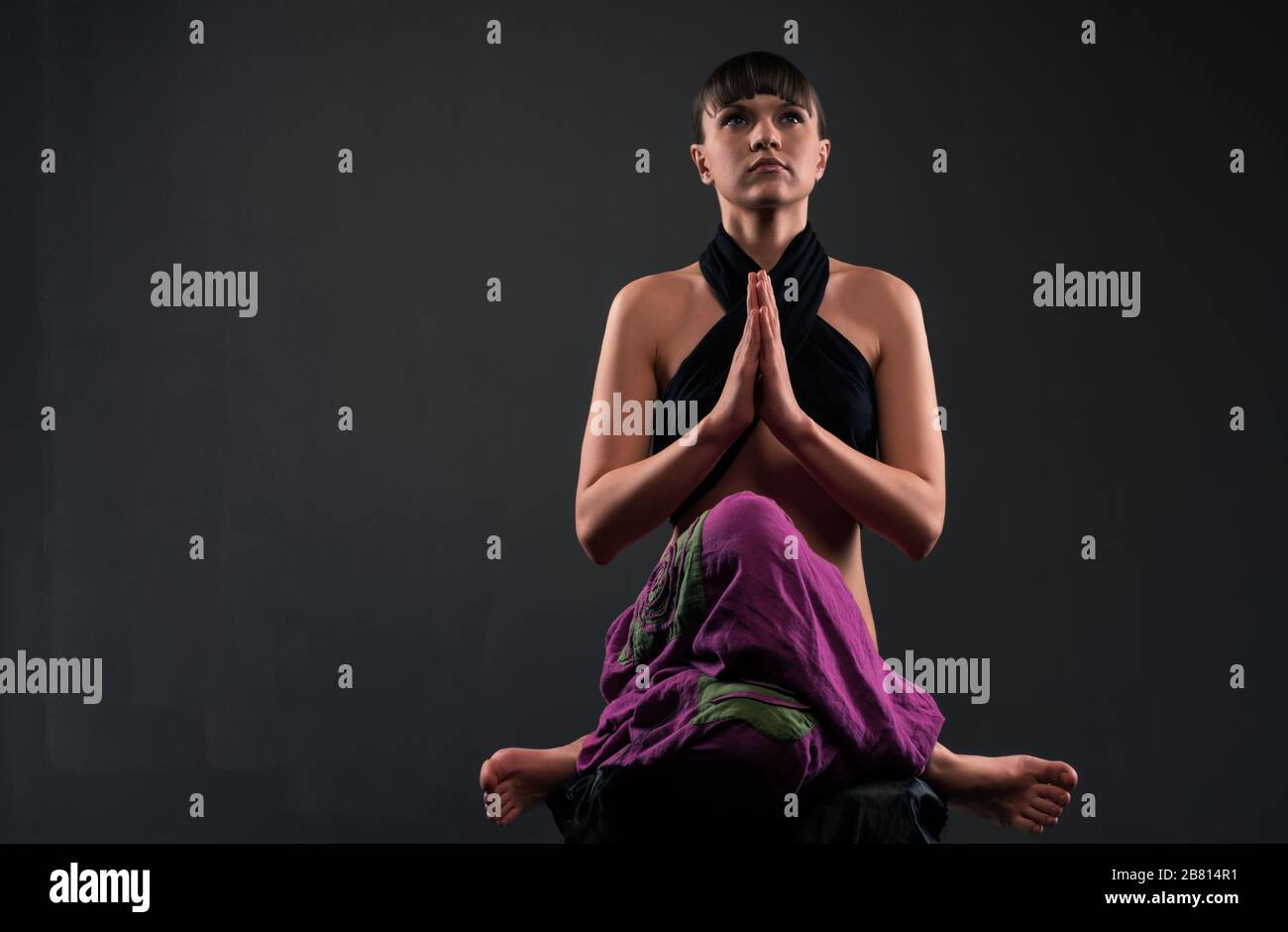 Front view of charming girl sitting in lotus position with prayer hands ...