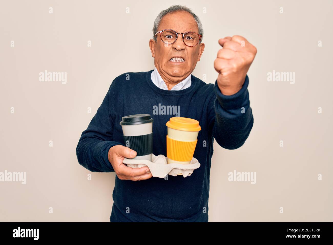 Senior handsome hoary man holding tray with takeaway cups of coffee ...