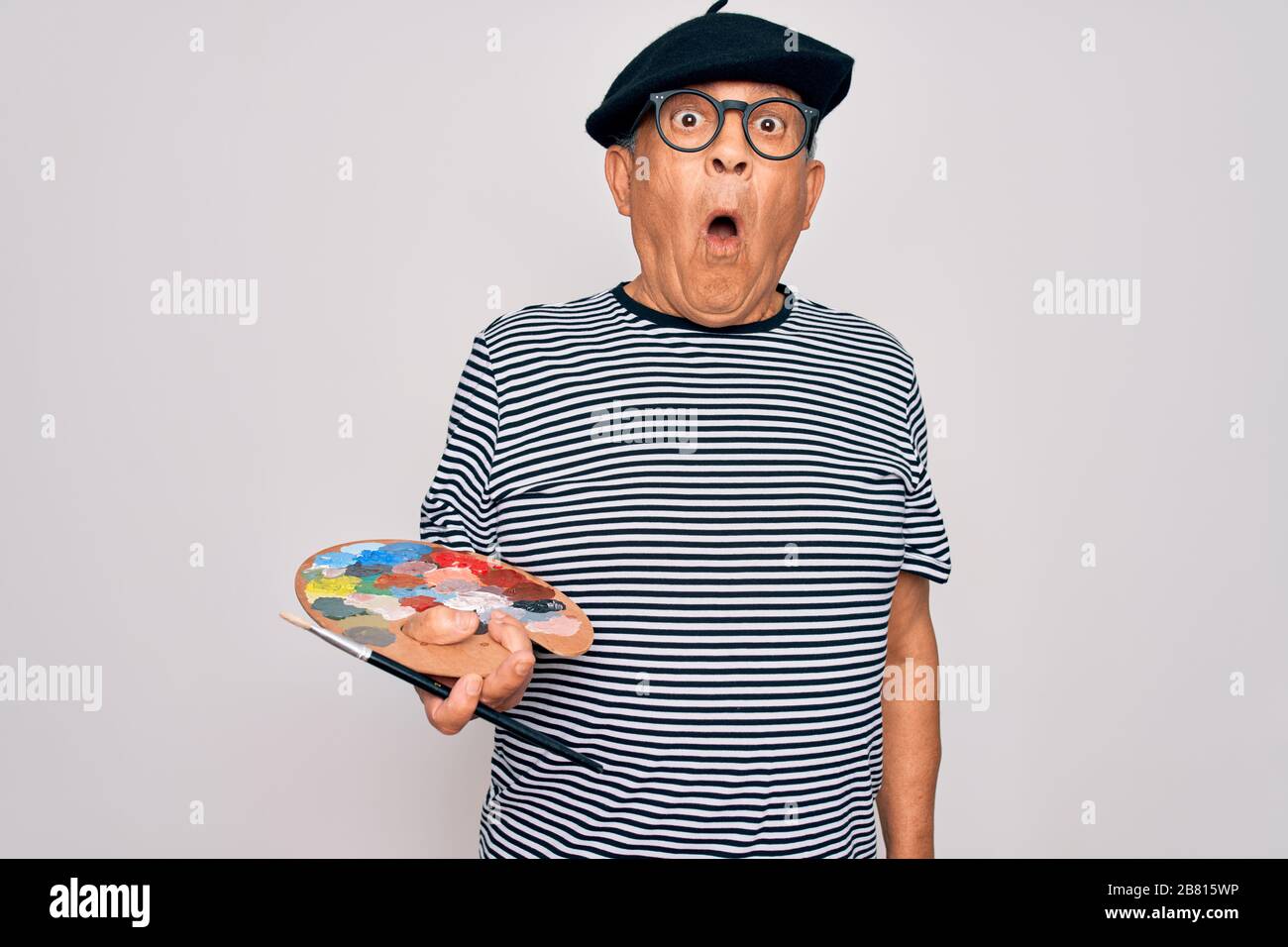 Senior hoary artist man wearing french beret drawing using paintbrush ...