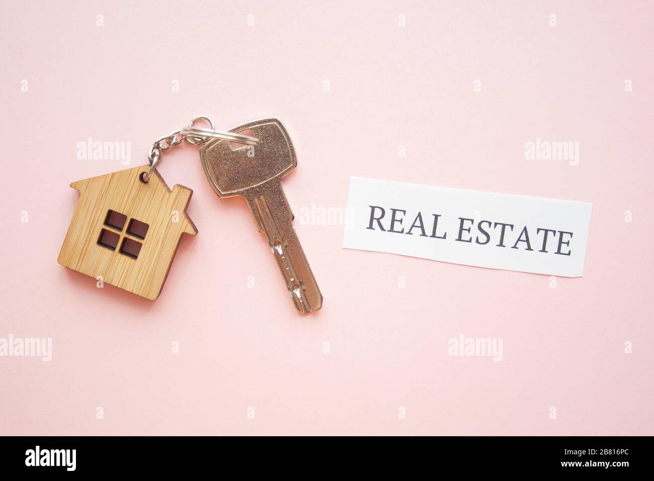 Wooden house toy and silver key on bright pink background with phrase ...