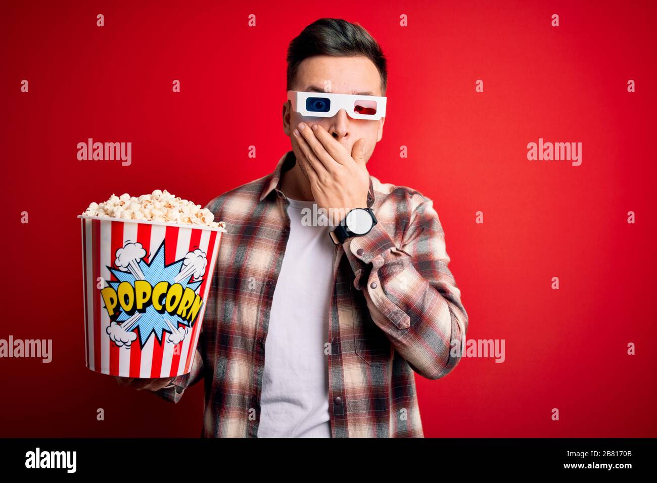 Young handsome caucasian man wearing 3d movie glasses and eating ...