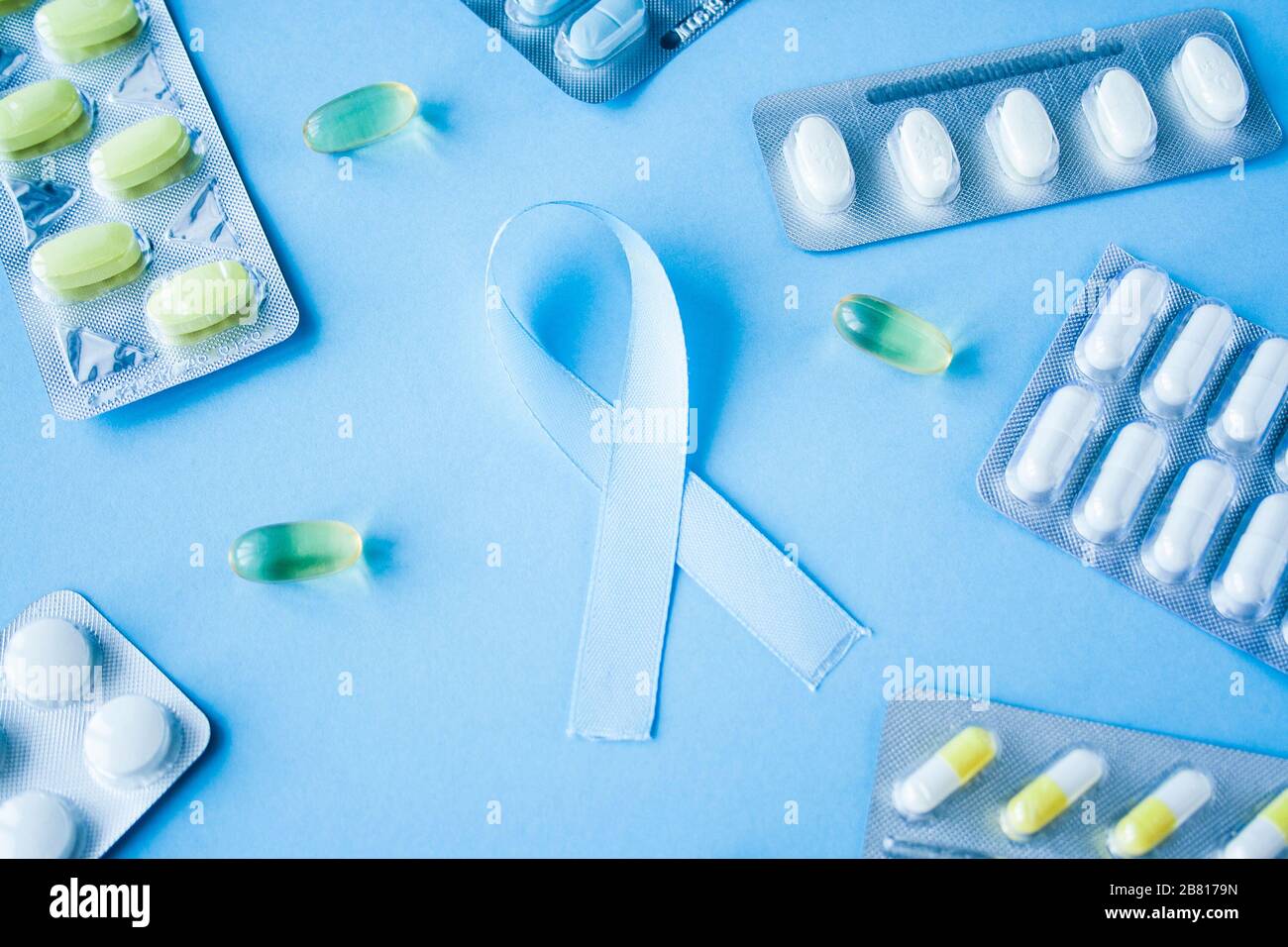 Blue ribbon symbol of prostate cancer with many pills and drugs ...