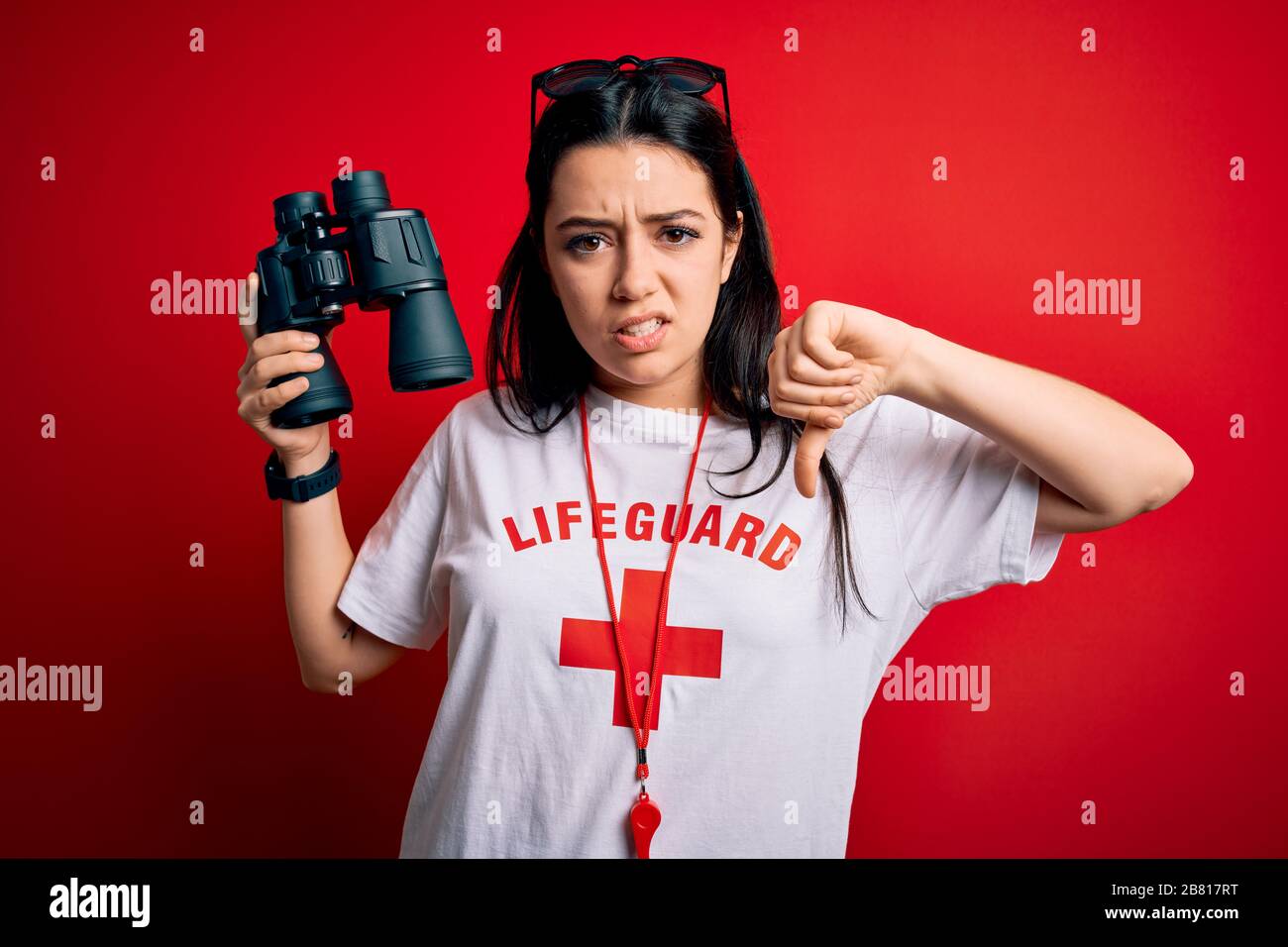 Young lifeguard woman wearing secury guard equipent holding binoculars ...