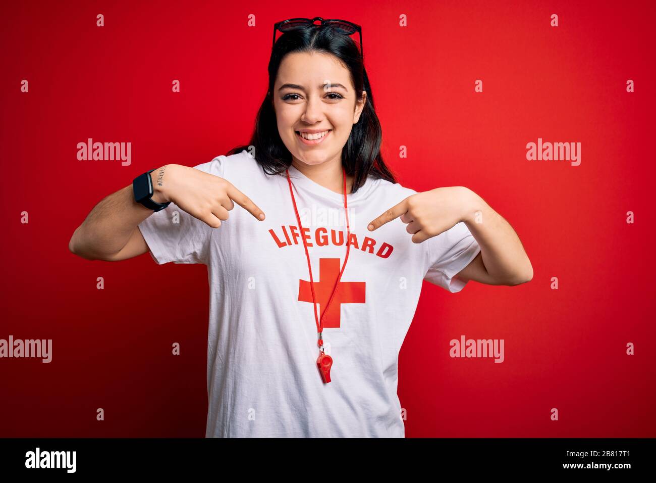 Young lifeguard woman wearing secury guard equipent over red background ...