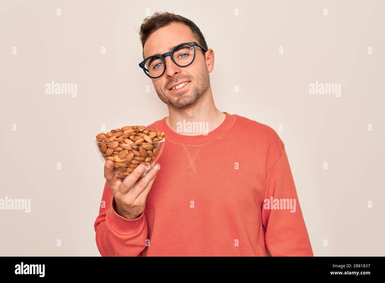 Handsome man with blue eyes holding bowl with healthy almonds snack ...