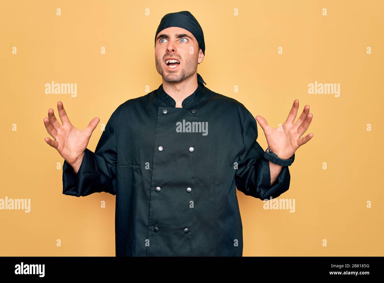 Young handsome cooker man with blue eyes wearing uniform and hat over ...