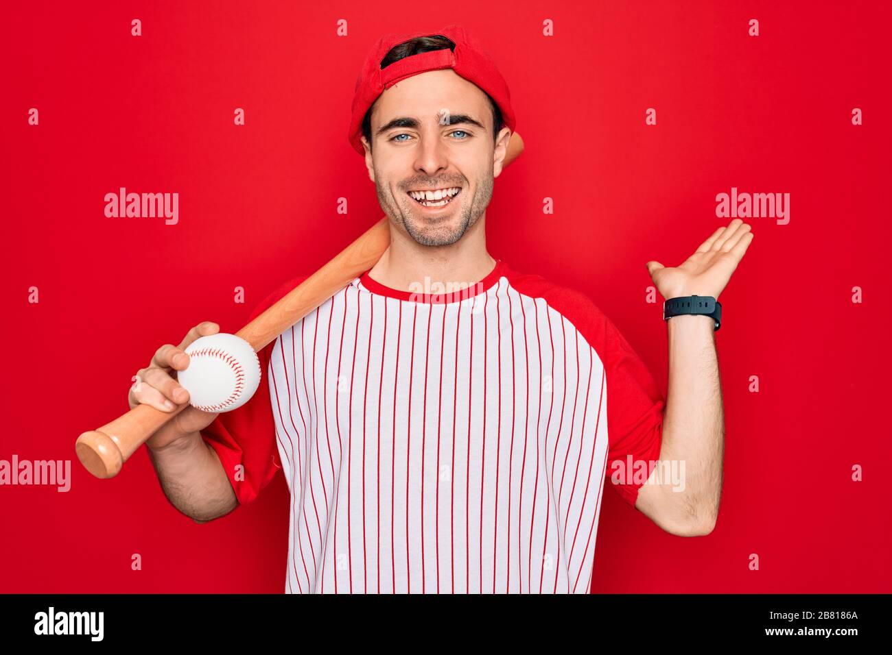 Young handsome sporty man with blue eyes playing baseball wearing cap ...
