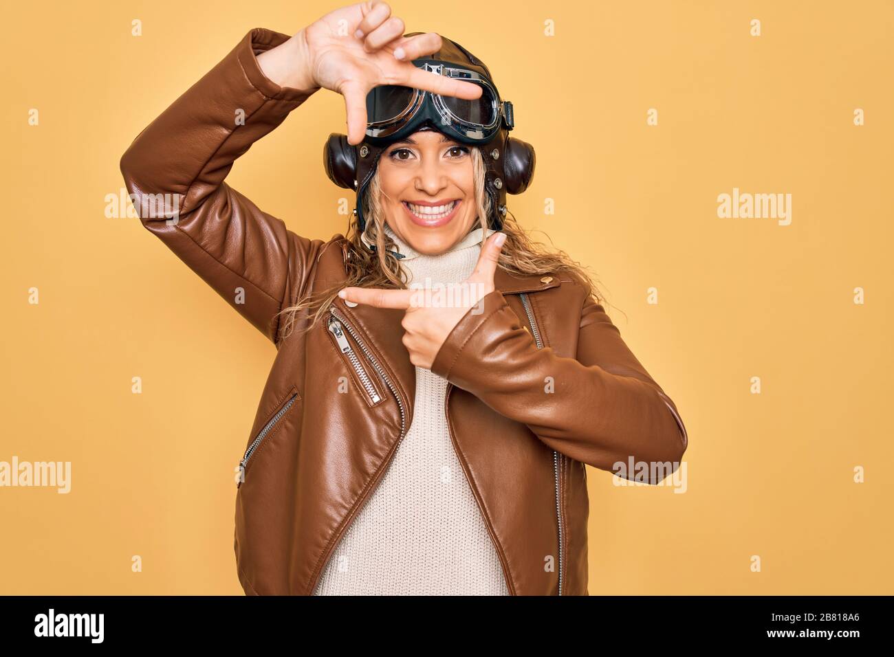 Young beautiful blonde aviator woman wearing vintage pilot helmet whit ...