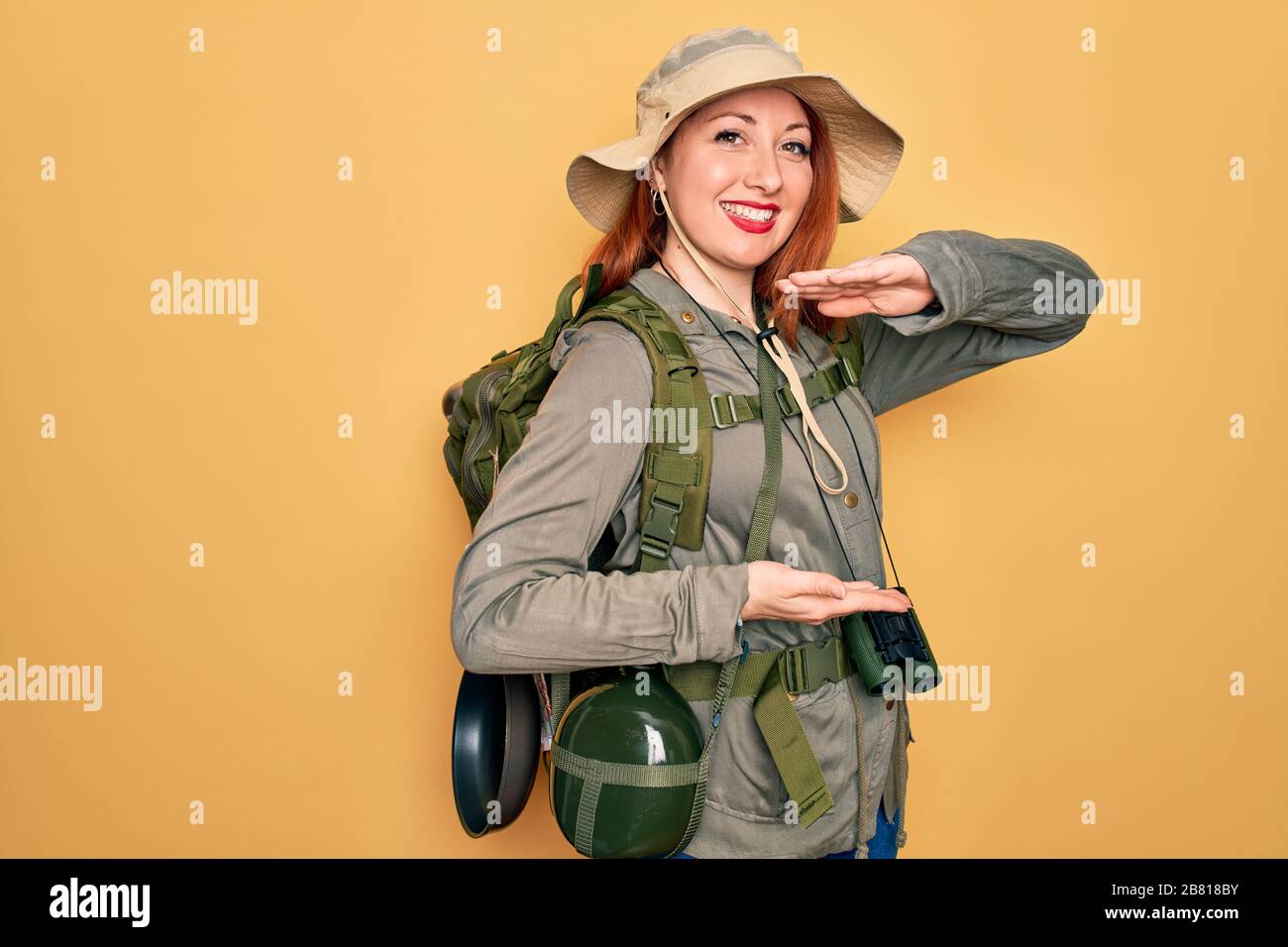 Young redhead backpacker woman hiking wearing backpack and hat over ...