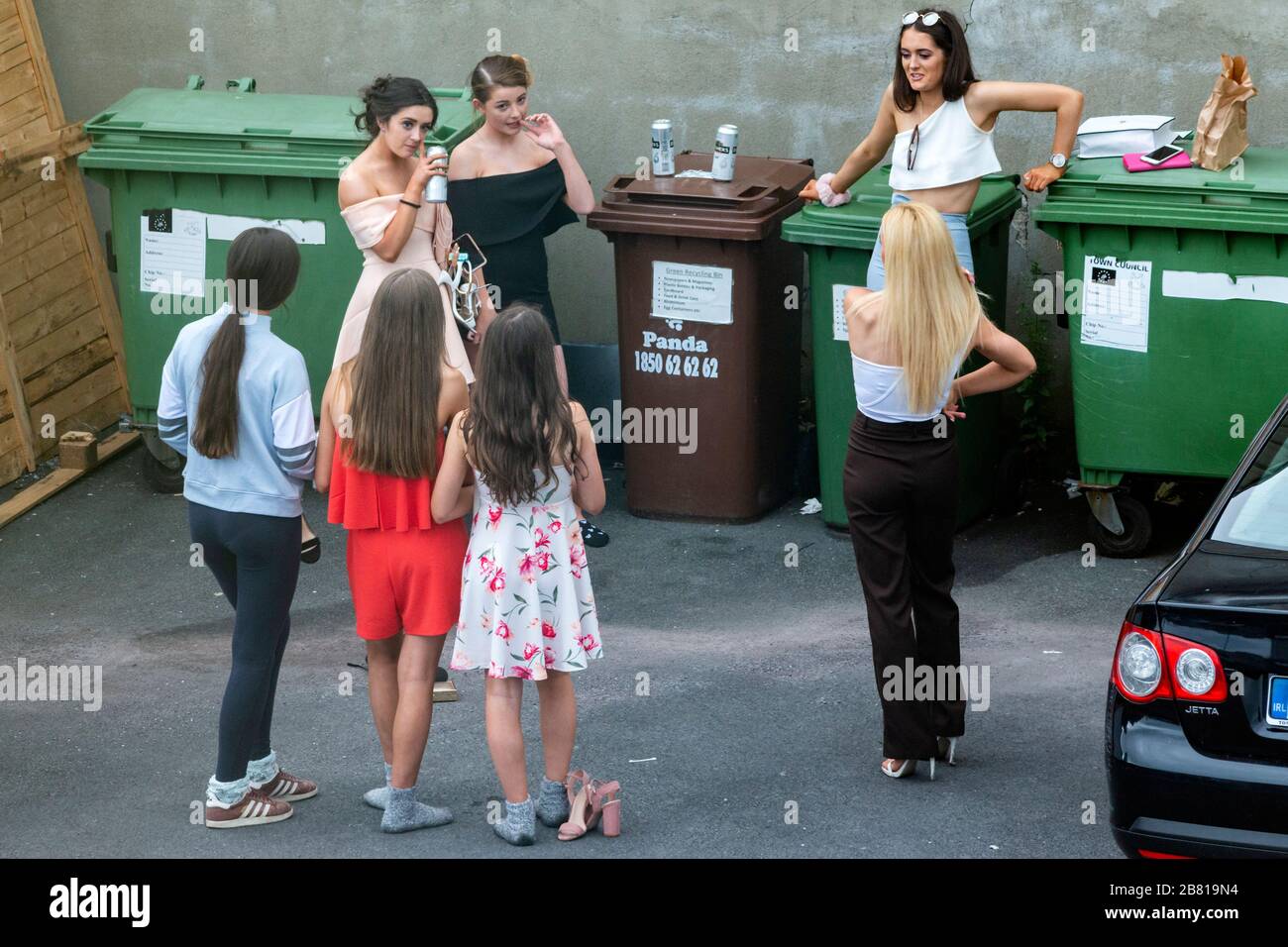 Young women and group of teenagers hanging out in smart prom dresses ...