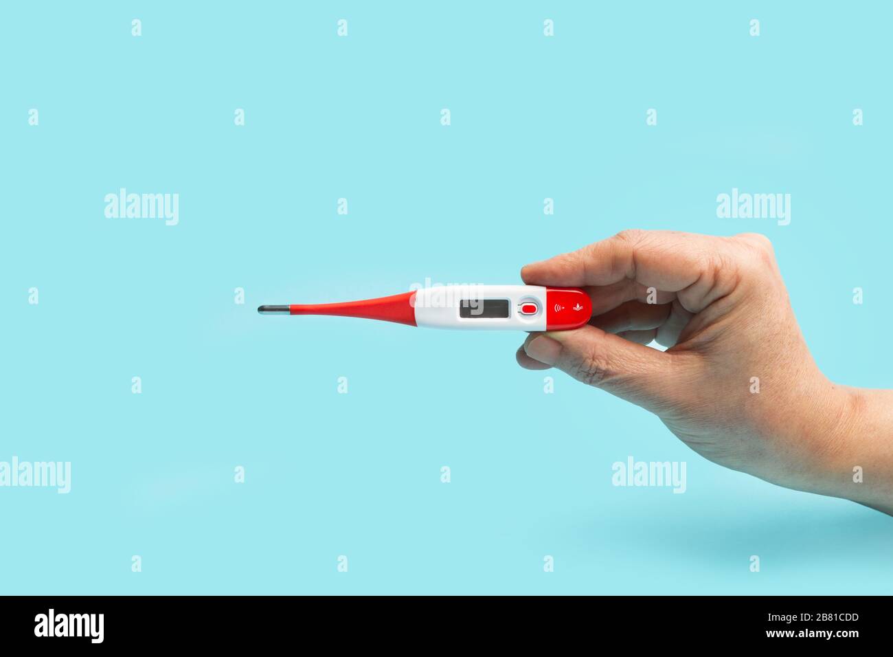 Woman hand holding a red and white thermometer on a light blue ...