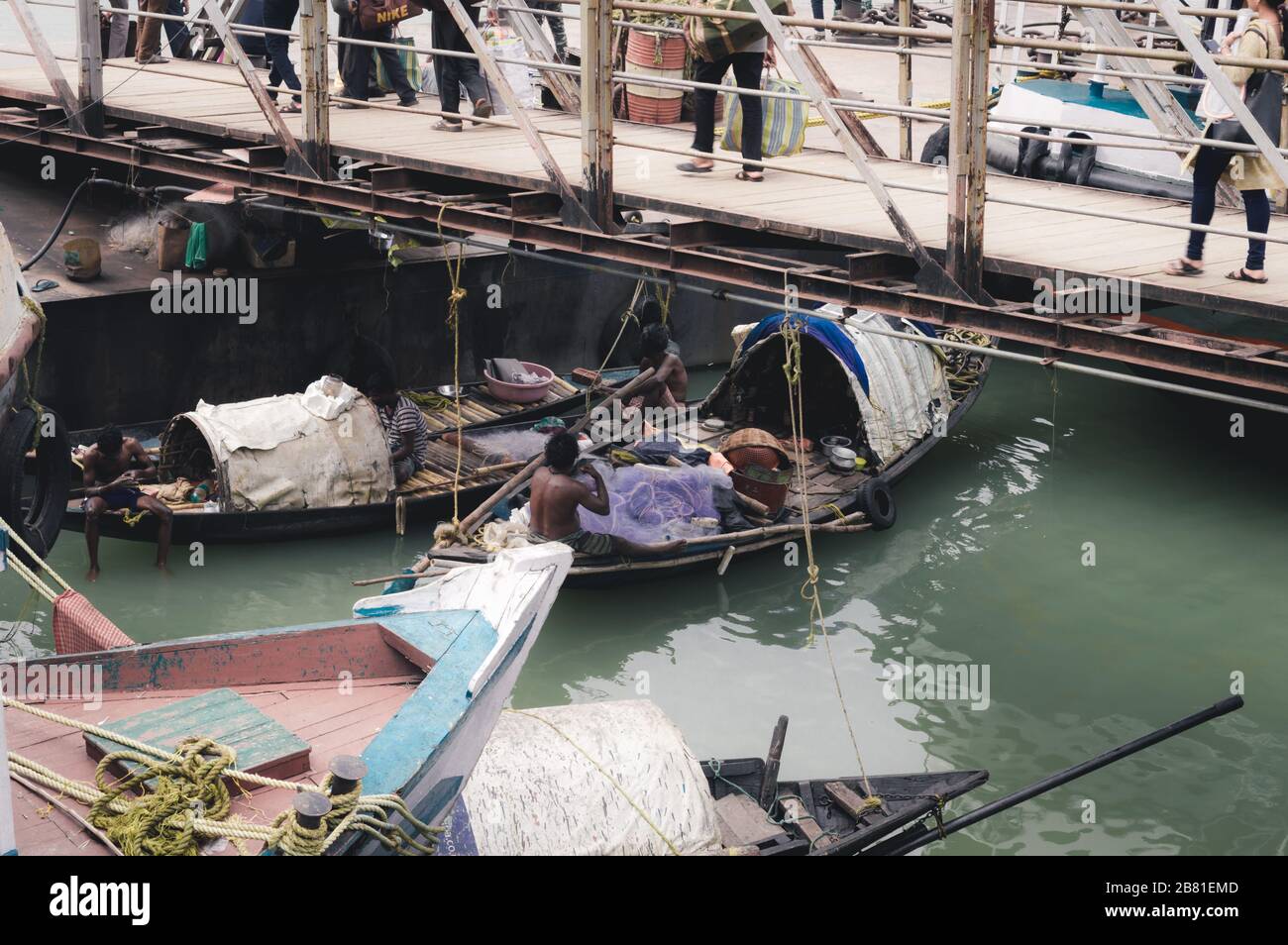 Fisherman sitting on a fishing boat under ferry terminal bridge ...