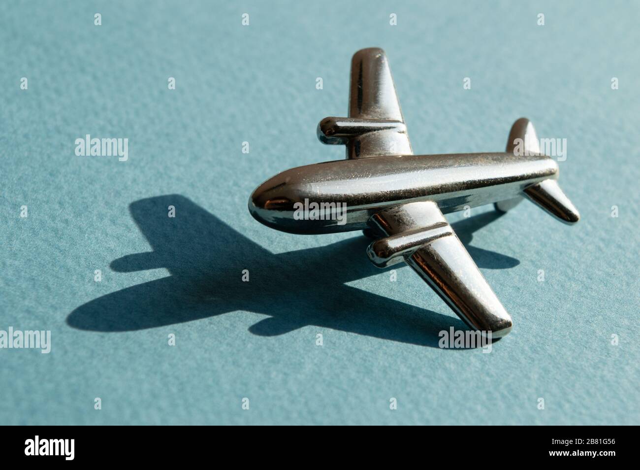 Metal figure of small airplane on the turqouise and light blue geometry ...