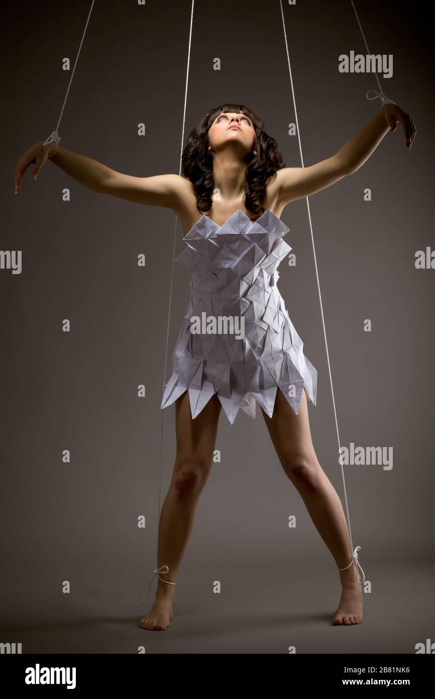 Portrait of a cute young sad girl in origami dress with moving arms ...