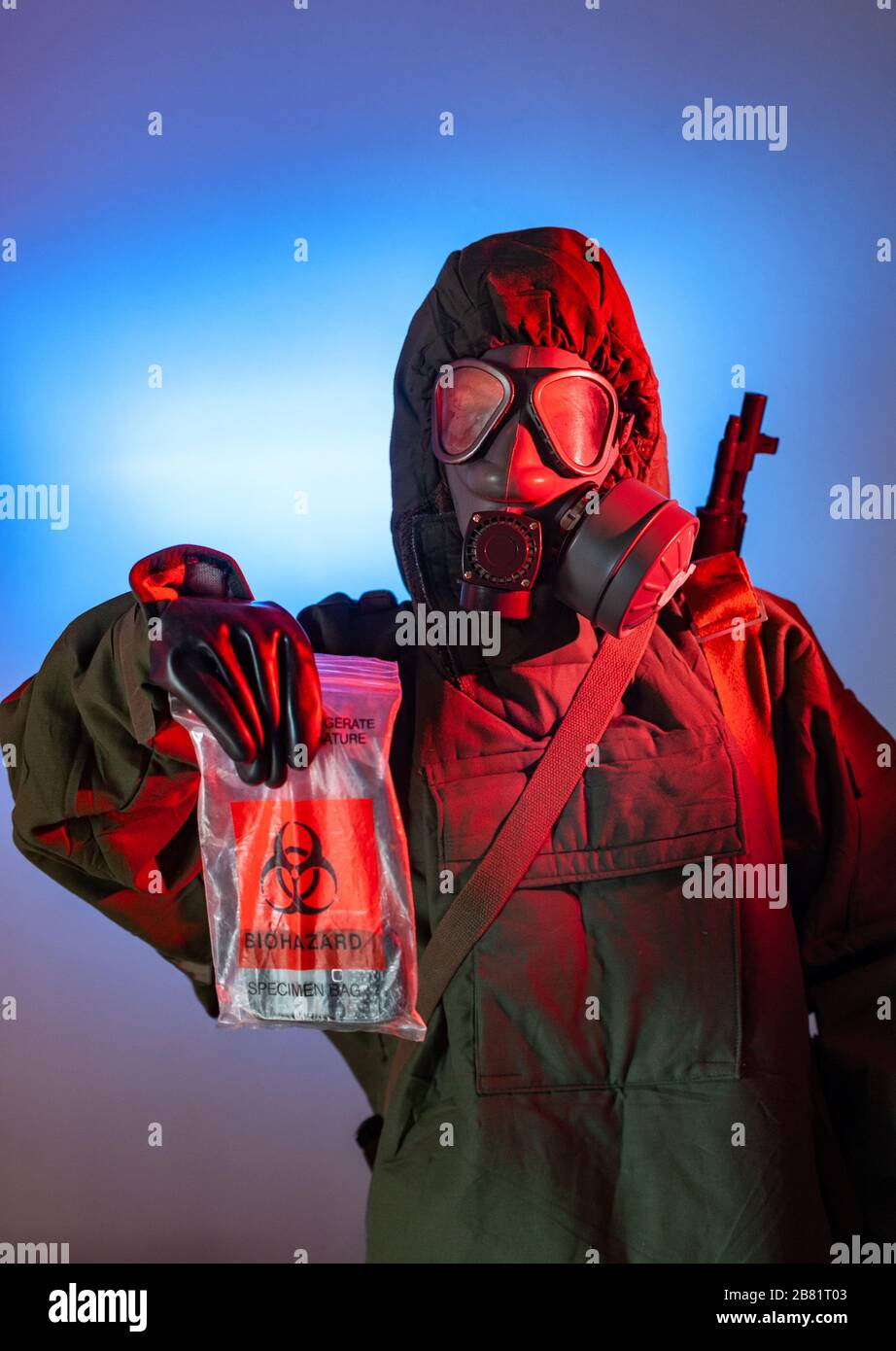 Man in Chemical warfare suit and mask holding biohazard bag, red and ...