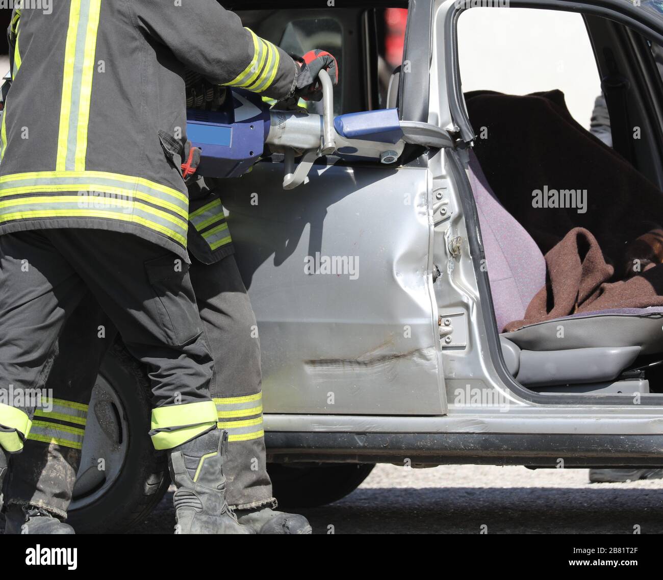 firefighter opens the damage car with big shear after the road accident ...