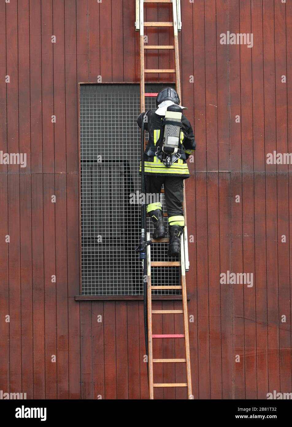 firefighter climbs the ladder with the oxygen cylinder during a rescue ...
