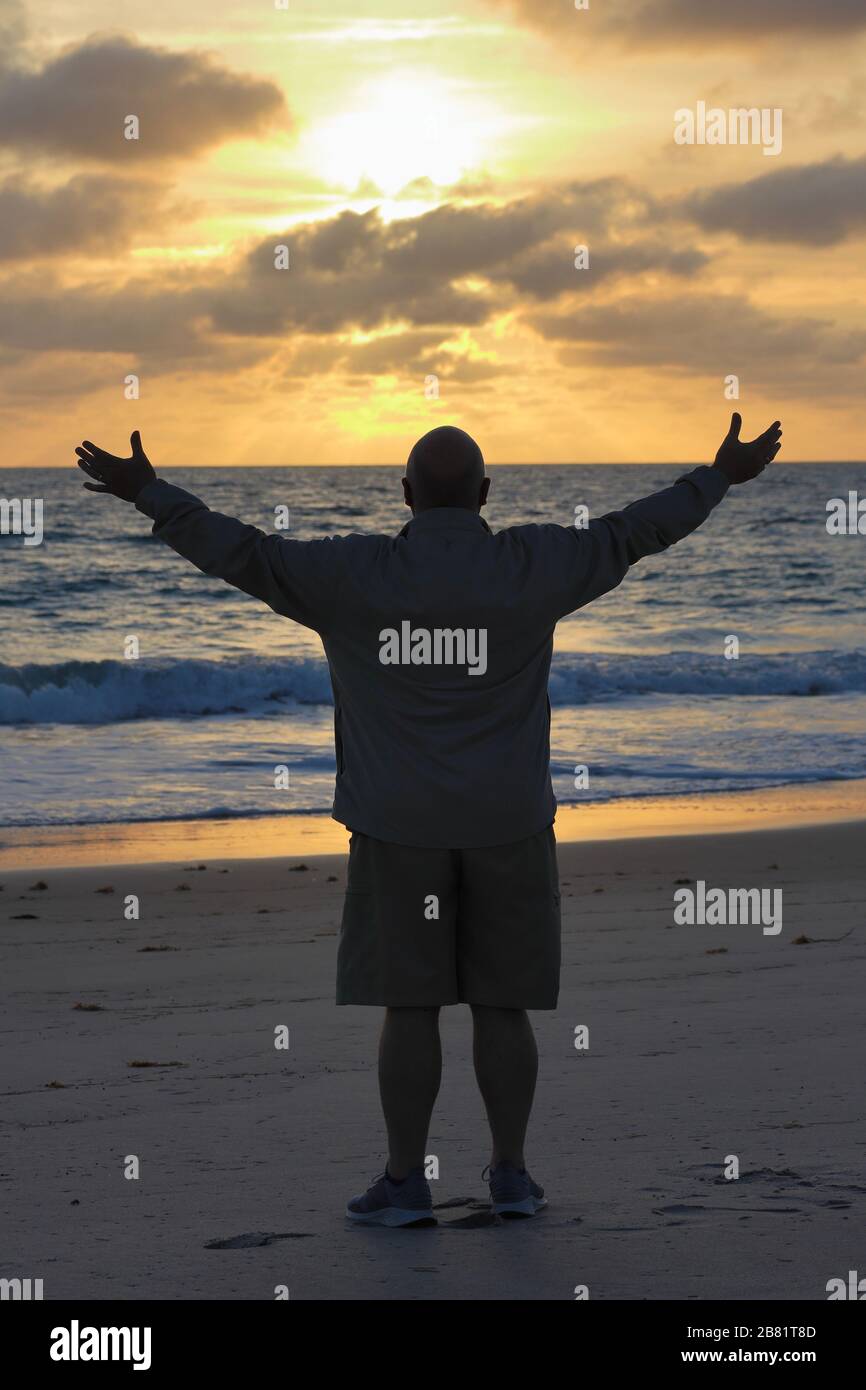A man greeting the sunrise at the beach on the Atlantic Ocean Stock ...
