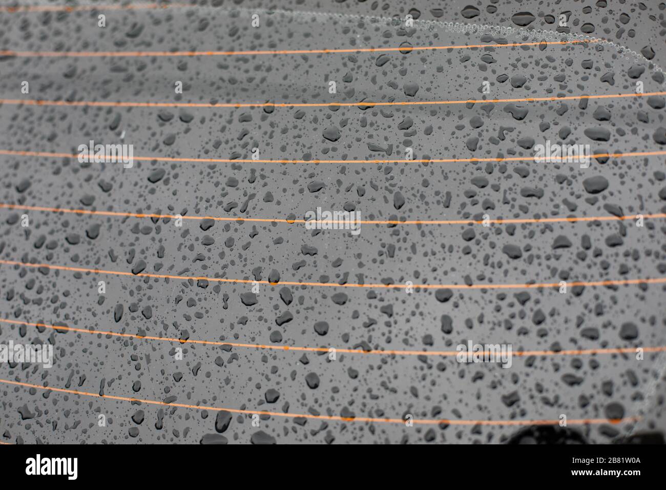 Drops of water on the rear window of the car, orange heating threads ...