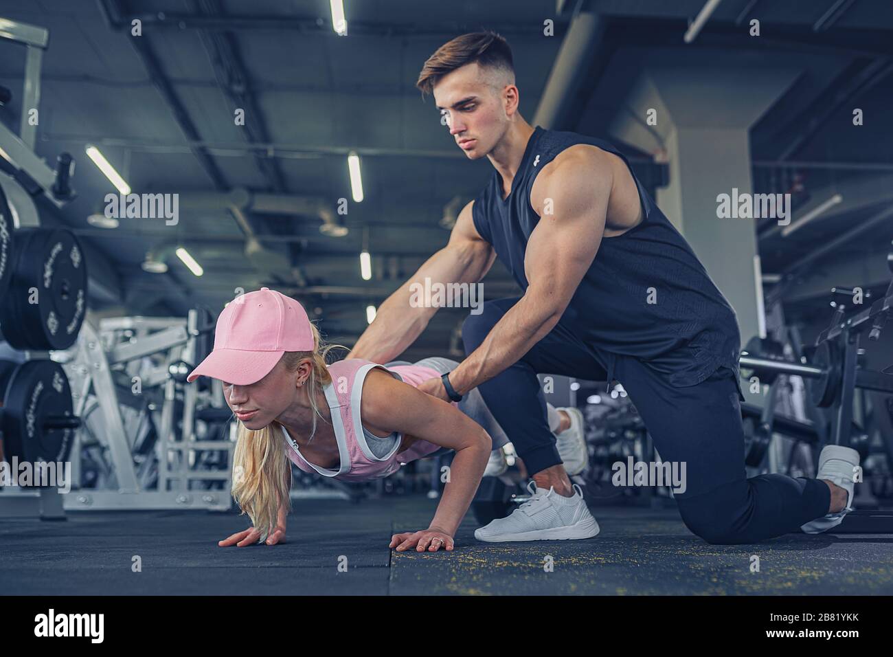 Fitness instructor help girl to do push ups on training in fitness center Stock Photo - Alamy