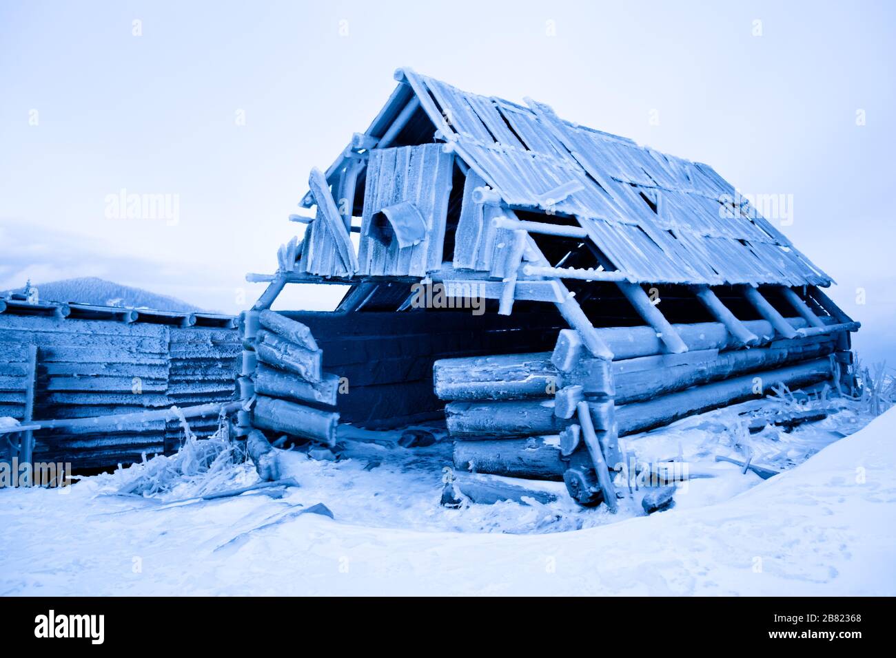 Abandoned house covered with frost over winter forest and snow ...