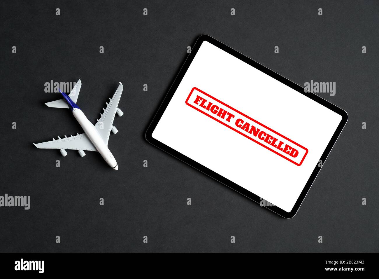 Flight cancelled concept. Plane model and tablet with sign "Flight ...
