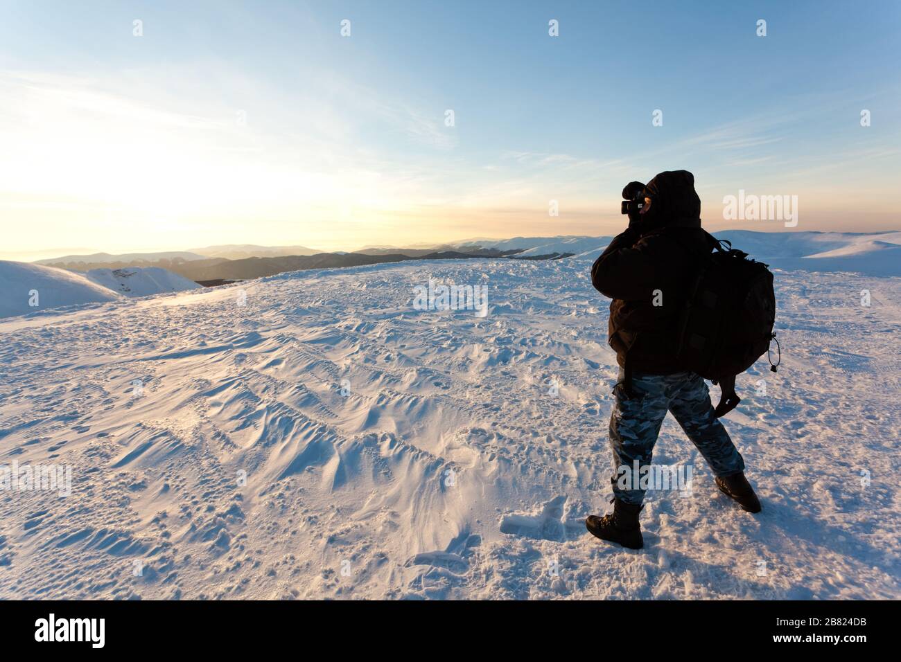 Young man photographer in winter clothing standing and making photo ...
