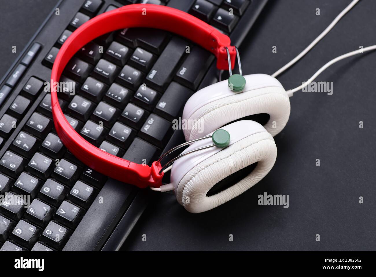 Earphones in red and white colors with computer keyboard. Headphones ...