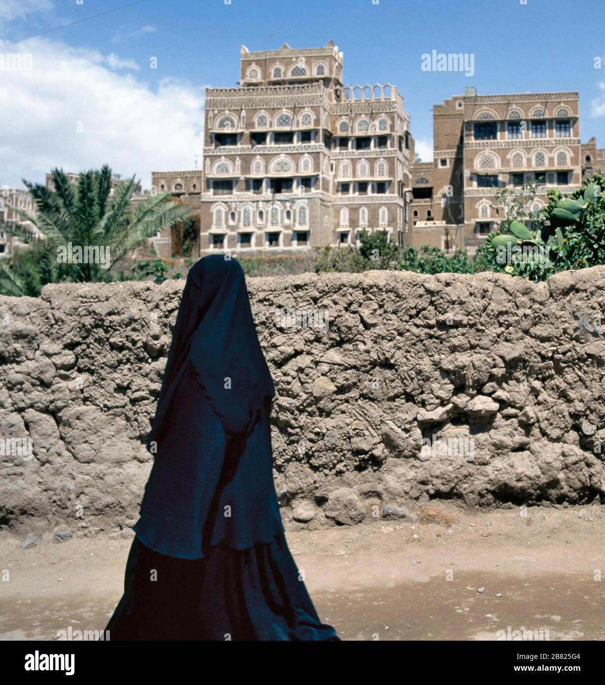 A veiled Muslim woman walks on a Sana a street, Yemen.At background ...
