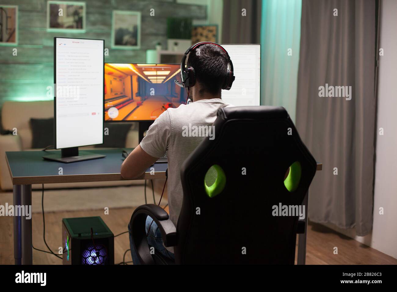 Back view of man sitting on gaming chair playing shooter game in the ...