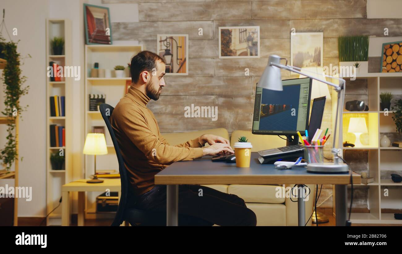 Side view of game developer working from home office on a new interface ...