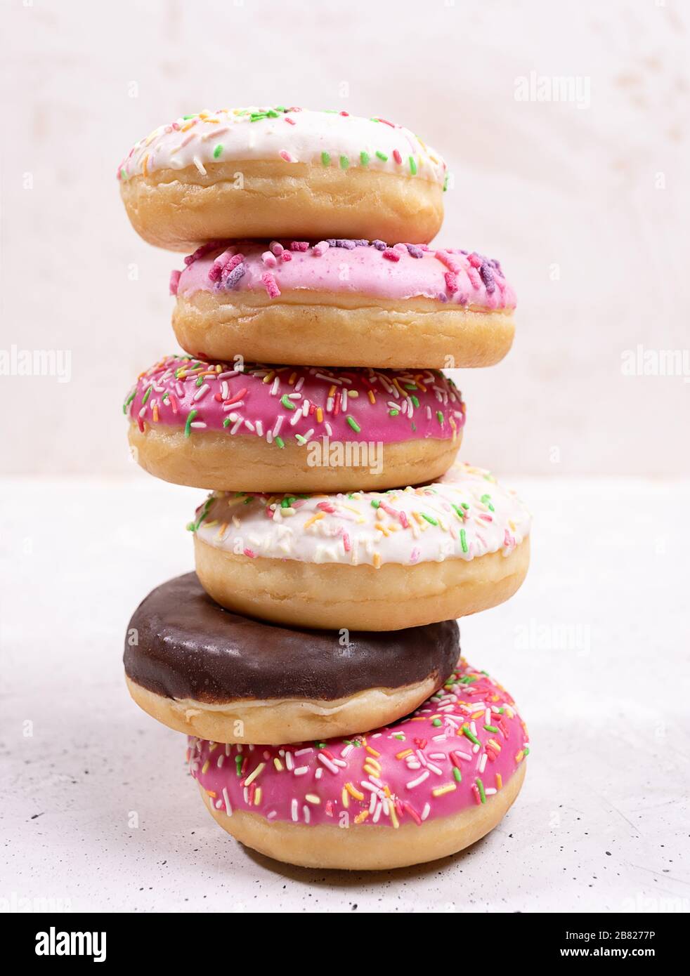 Stack of six doughnuts with multicolored glaze on white background ...