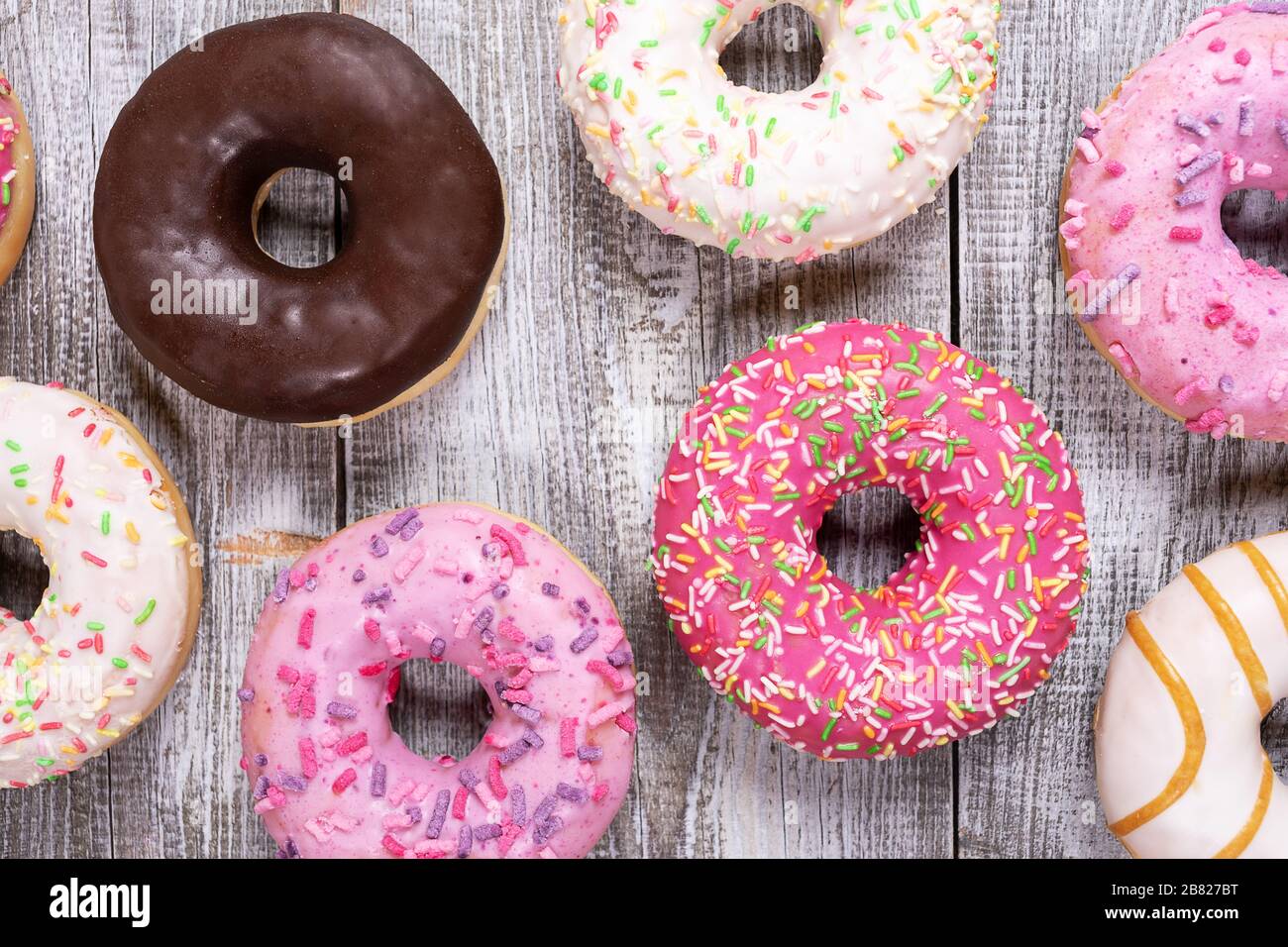 Traditional doughnuts with multicolored glaze laid out on white painted ...