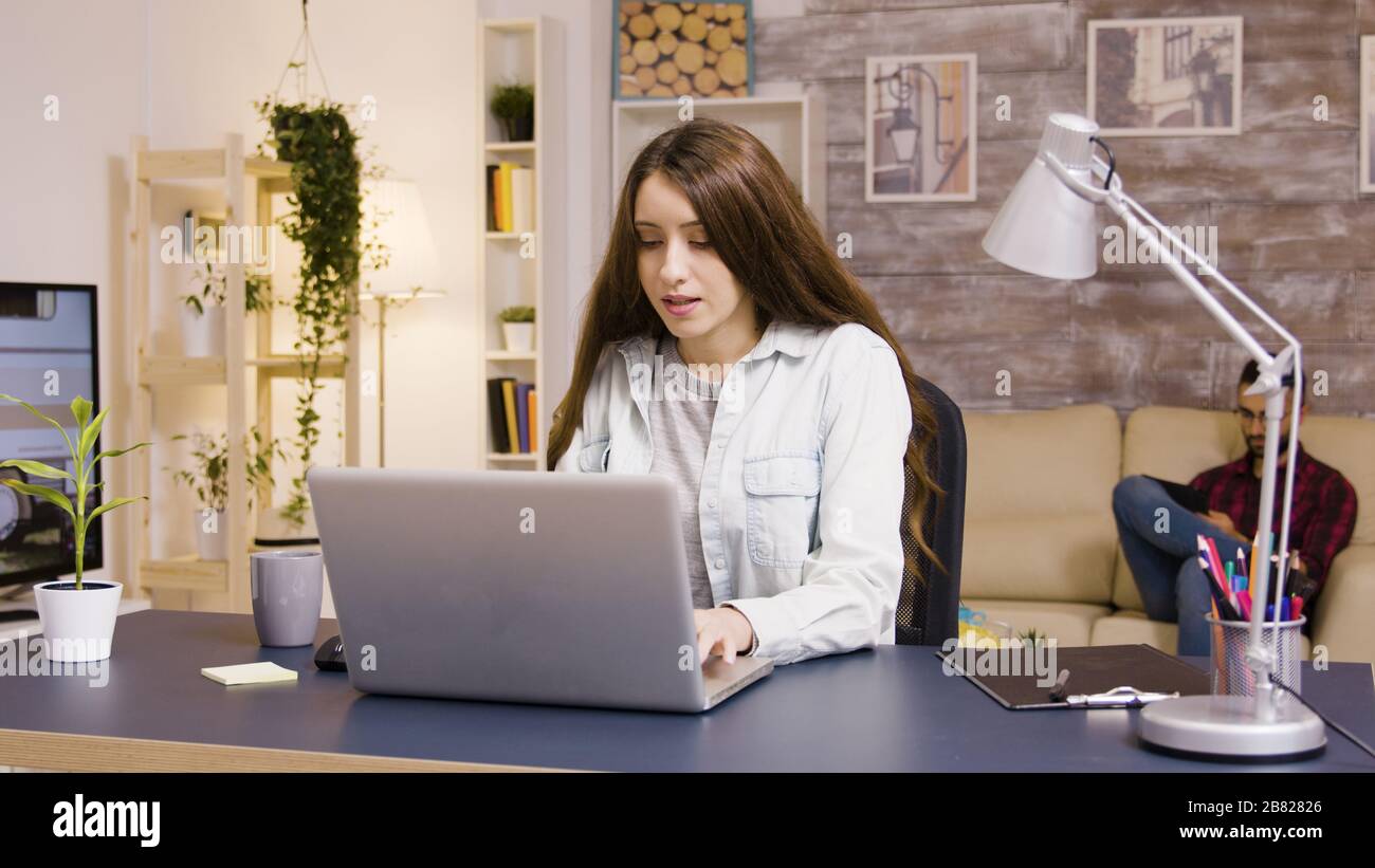 Girl typing on laptop while working from home. Boyfriend in the ...