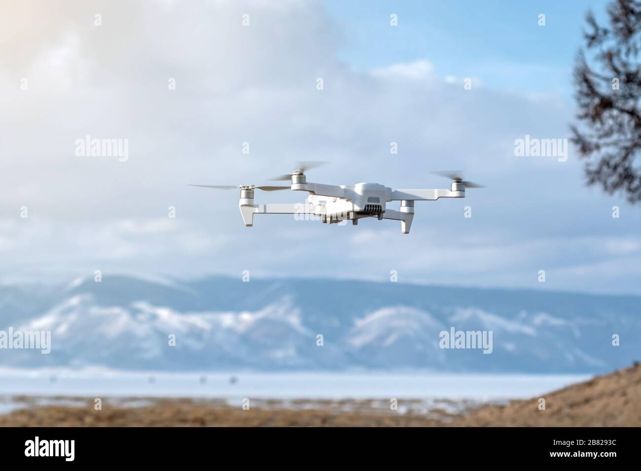 White quadrocopter drone with camera hangs in the air on the background ...
