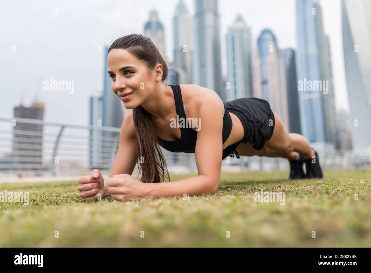 Young fit woman make plank exercises in front of skyscrapers Stock ...