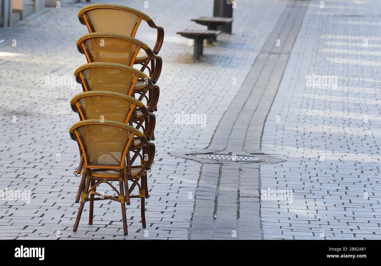 19 March 2020, Bavaria, Kempten: Chairs of a street café are stacked on ...