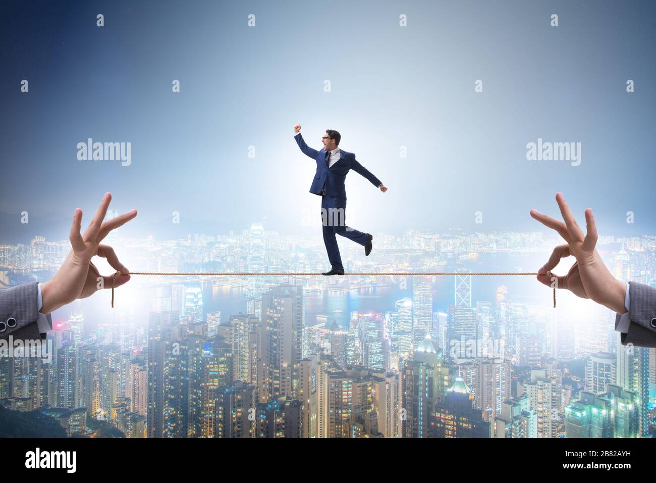 The businessman walking on tight rope Stock Photo - Alamy
