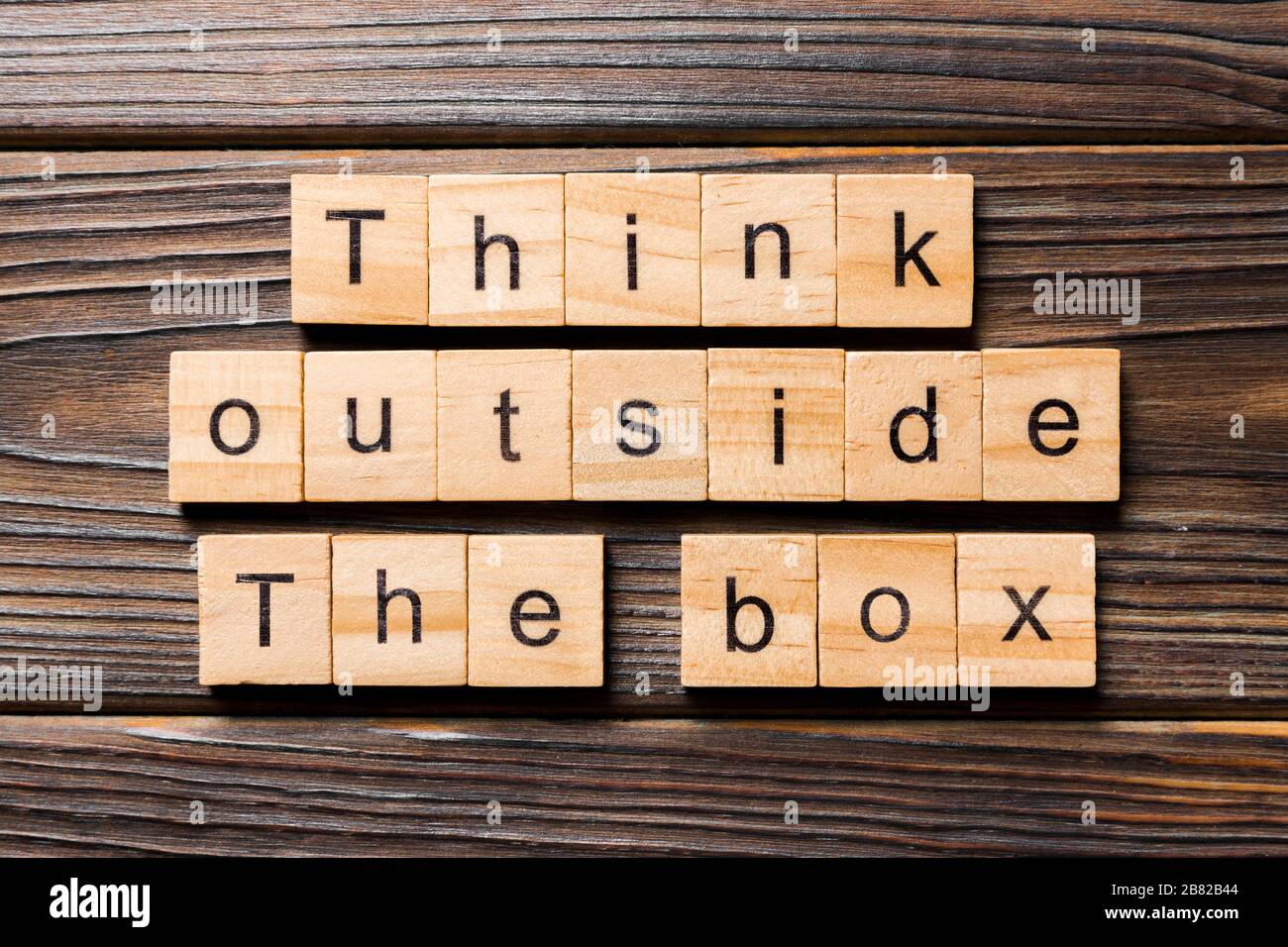 Think outside the box word written on wood block. Think outside the box text on wooden table for ...