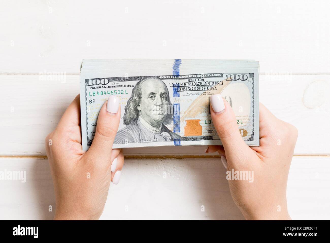 Top view of female hands counting money. One hundred dollar banknotes ...