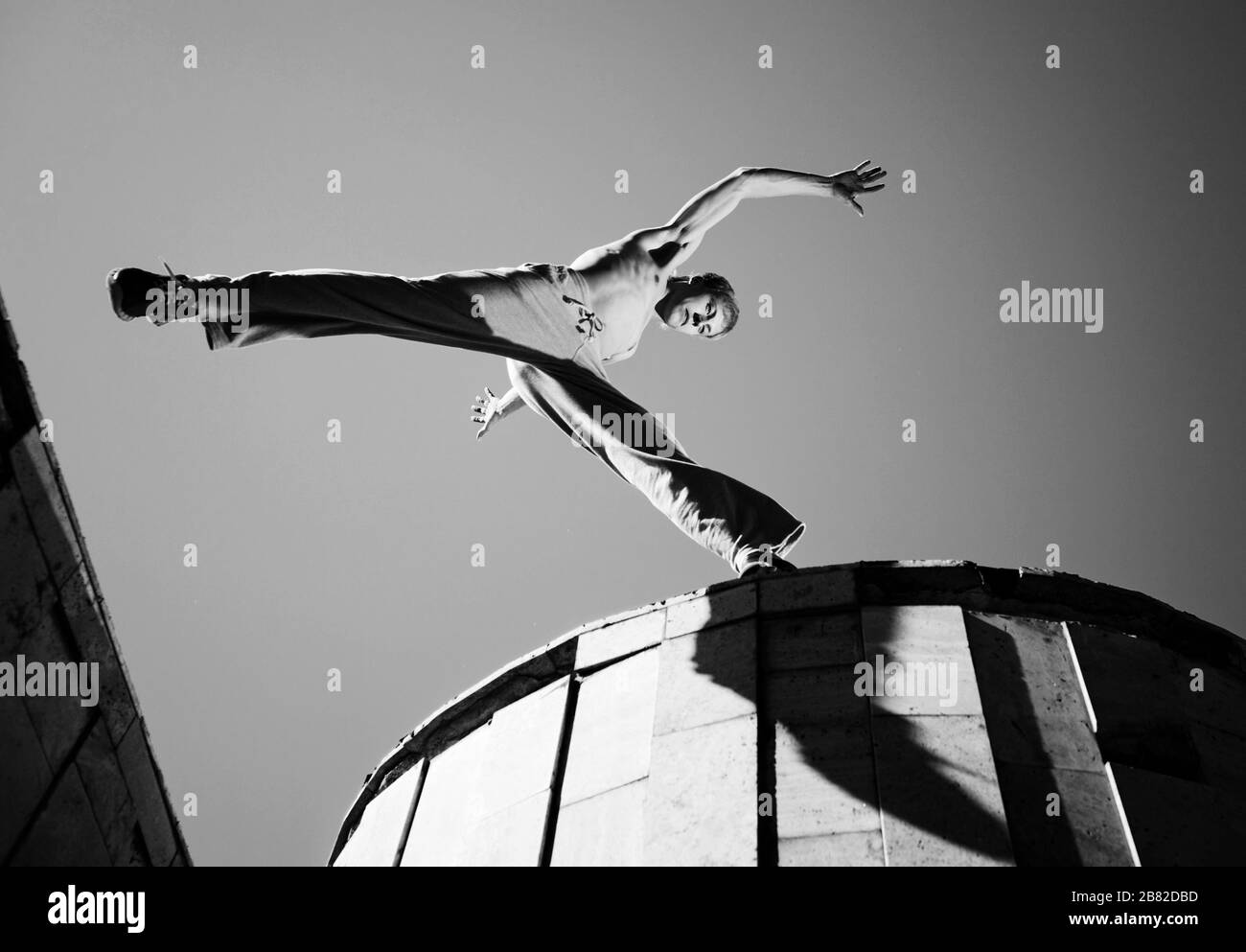 Young man jumping and practicing parkour between buildings roofs ...
