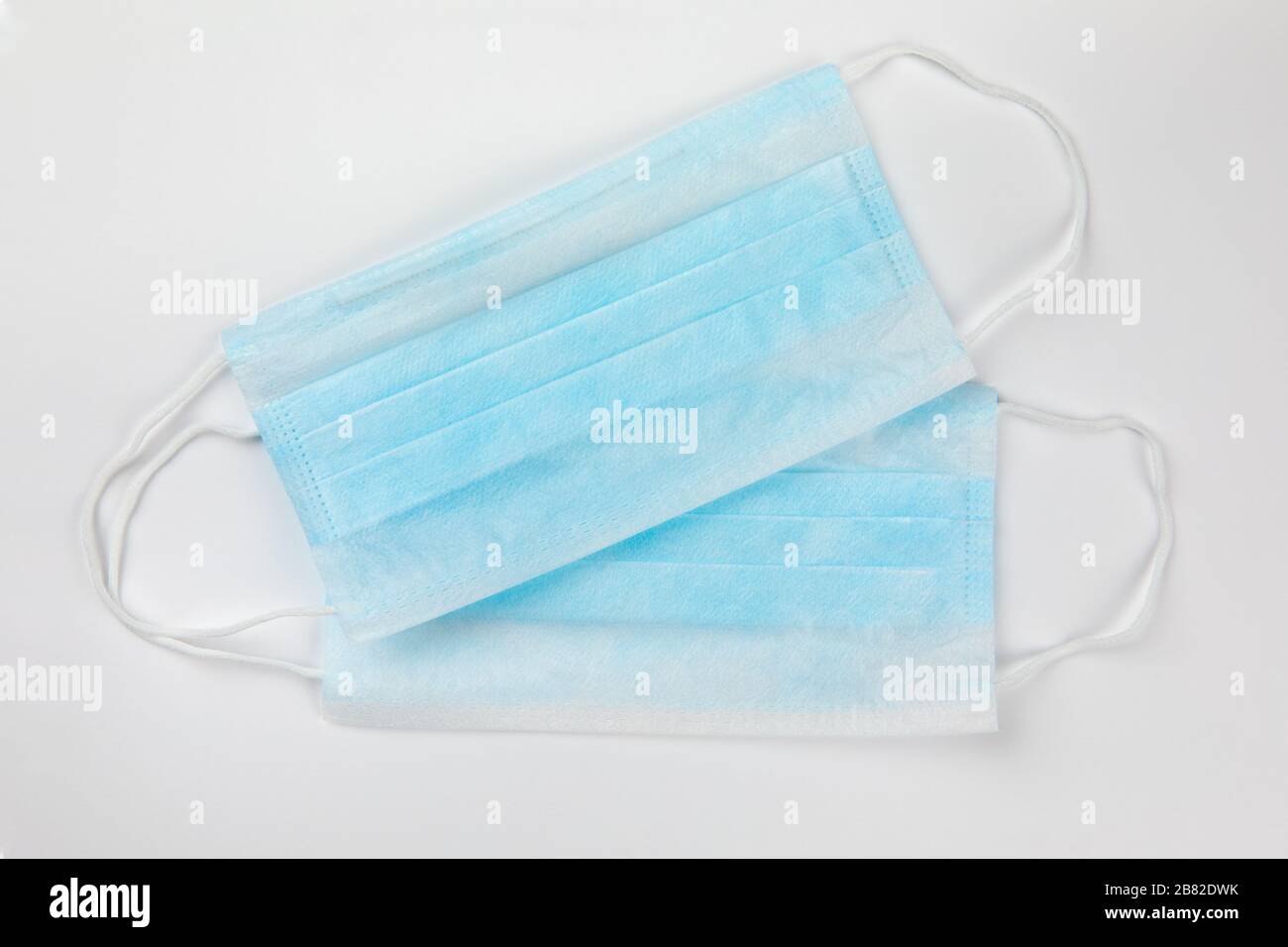 two blue surgical medical masks on white background Stock Photo - Alamy