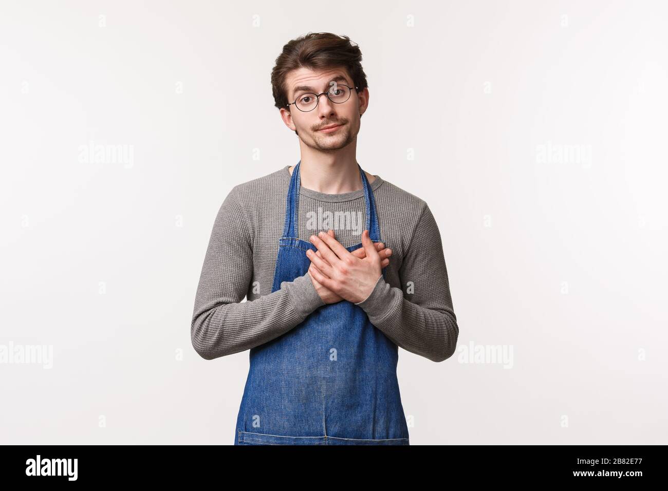 Portrait of touched sarcastic young man in apron acting like he care ...