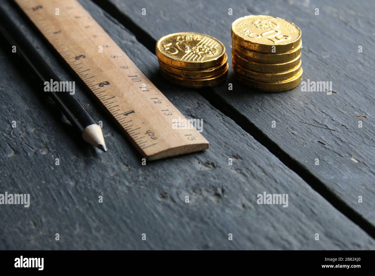 Piles of gold coins, a pencil and a ruler on the table Stock Photo - Alamy